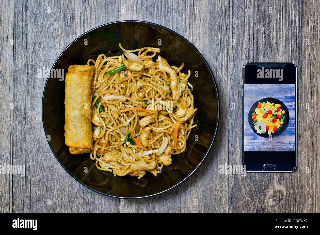 Bowl of Asian noodles on a rustic wooden table with a generic ...