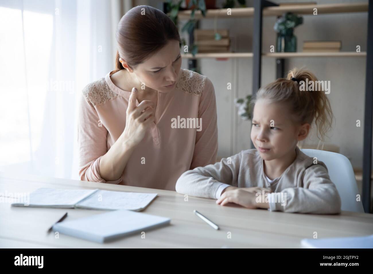 Unhappy young mother scolding small kid for bad marks Stock Photo - Alamy