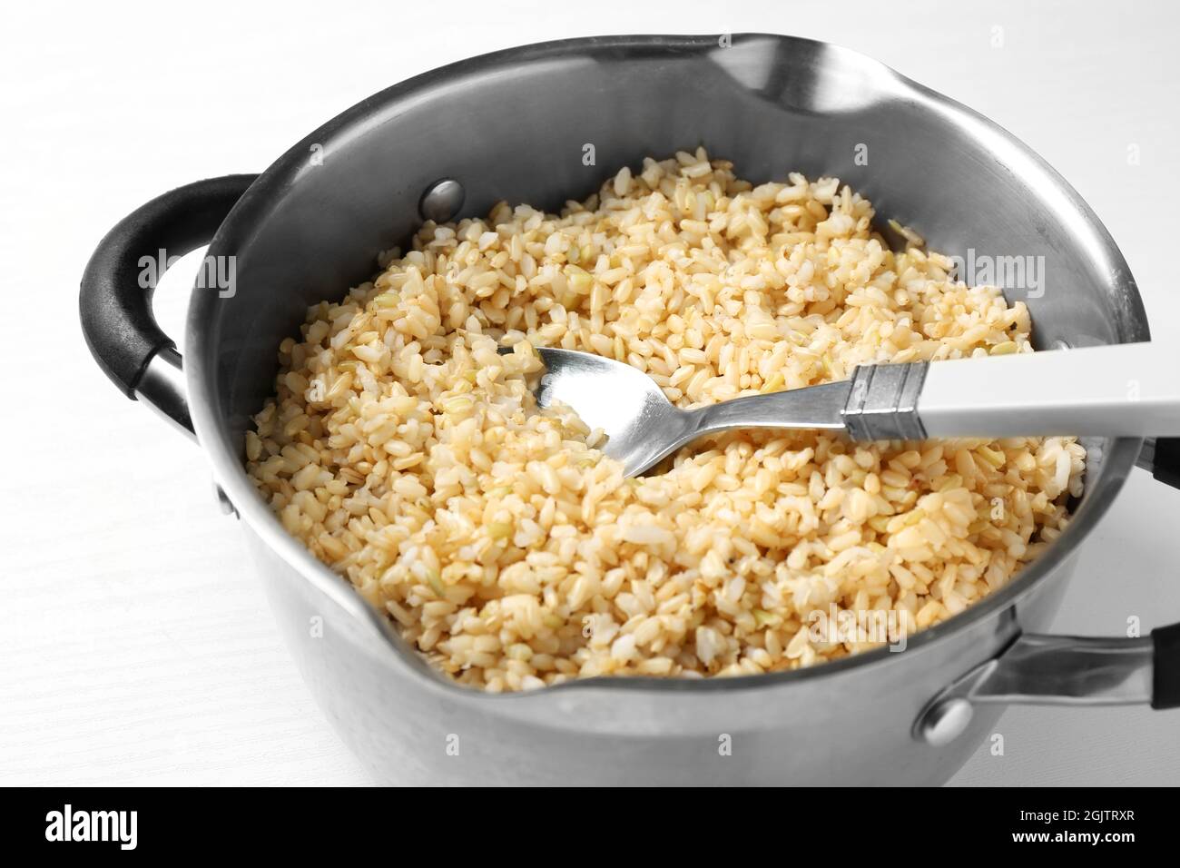 Pan with boiled brown rice on white background Stock Photo - Alamy