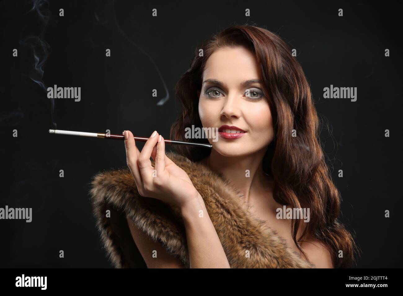 Beautiful woman smoking cigar on dark background Stock Photo - Alamy