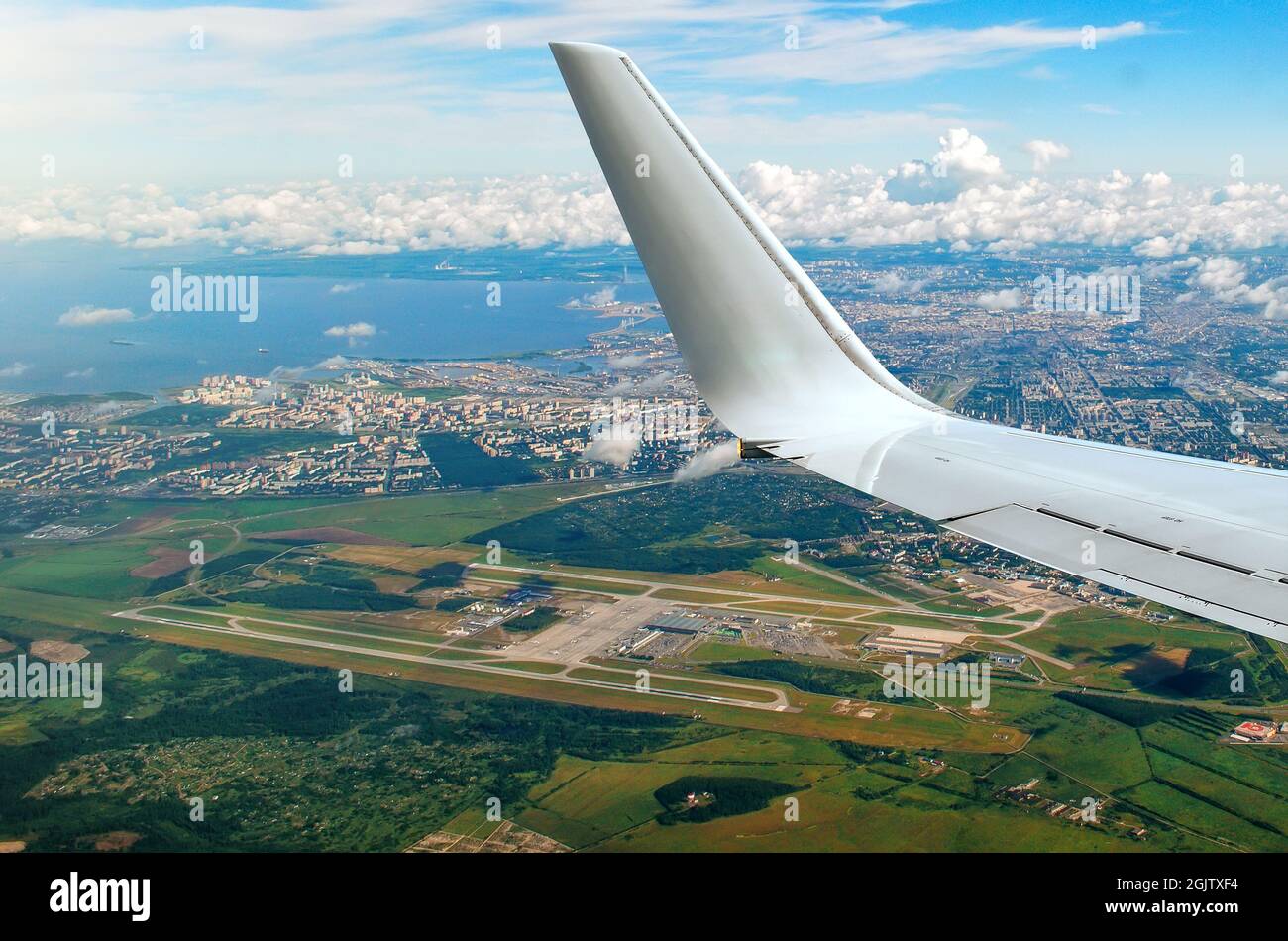 Wing view from the airplane window to the wing, airport, sea, city and ...
