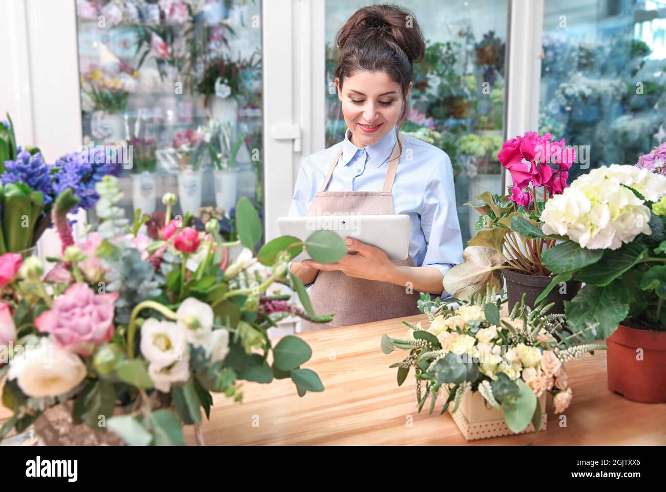 Beautiful woman florist with tablet at flower shop Stock Photo - Alamy