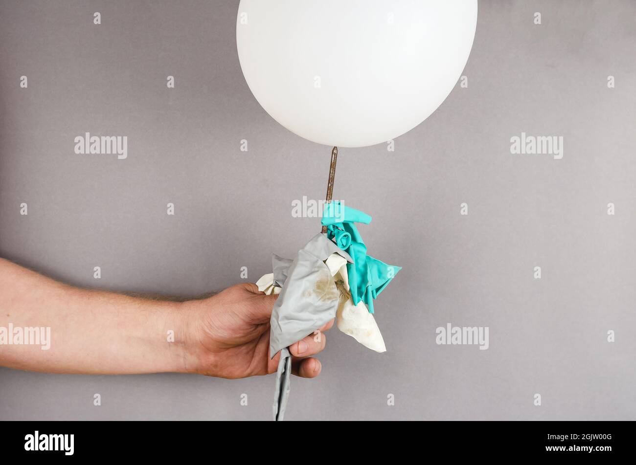 A man's hand pierces a balloon against a gray background. Person Stock ...