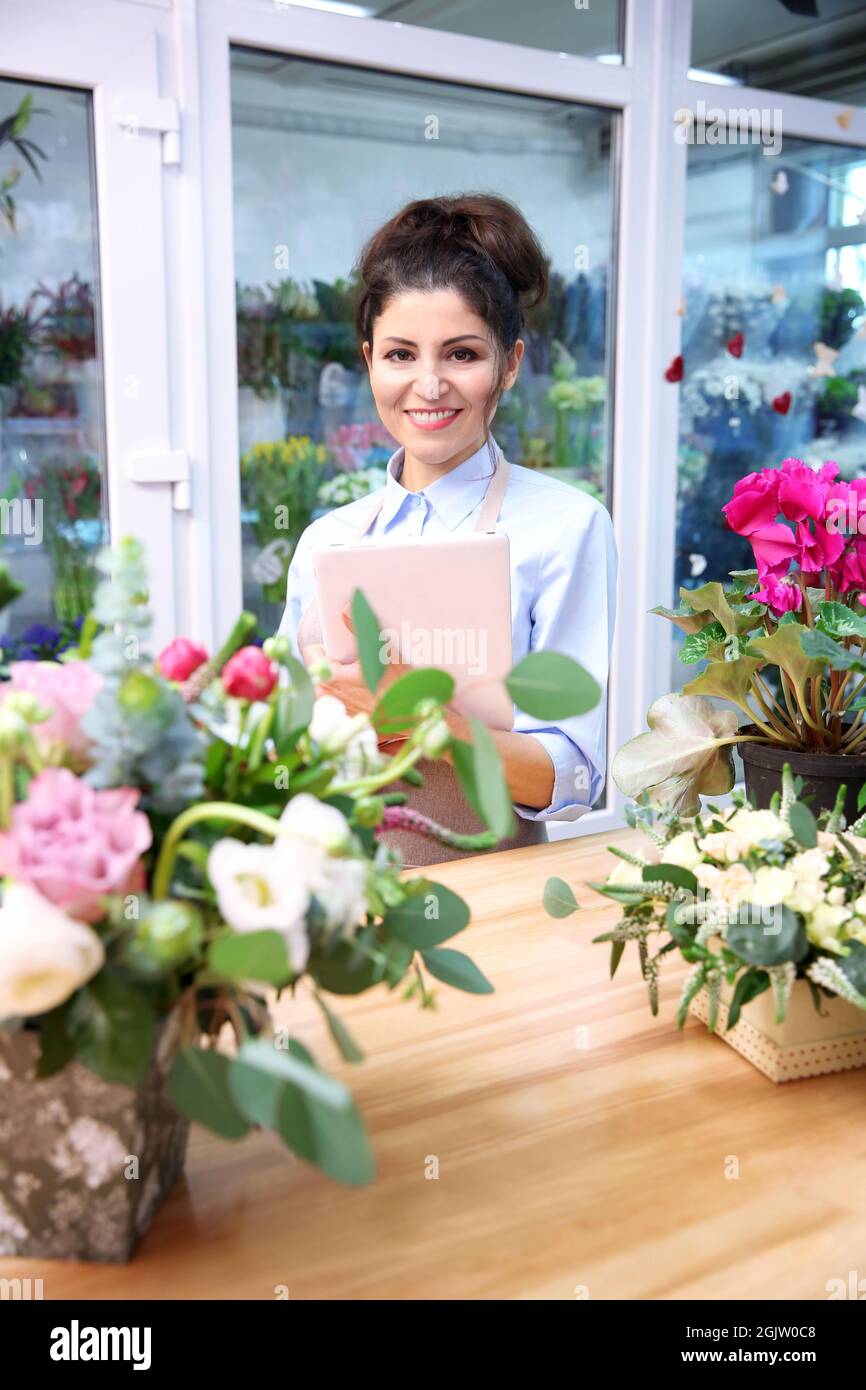 Beautiful woman florist with tablet at flower shop Stock Photo - Alamy