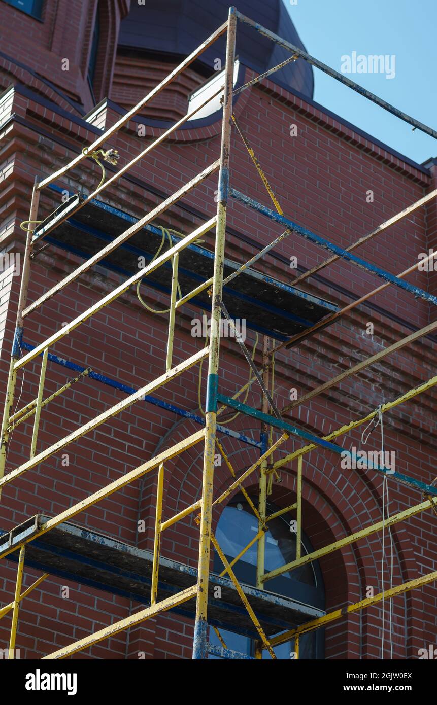 Yellow scaffolding in front of the red brick building. Construct Stock ...