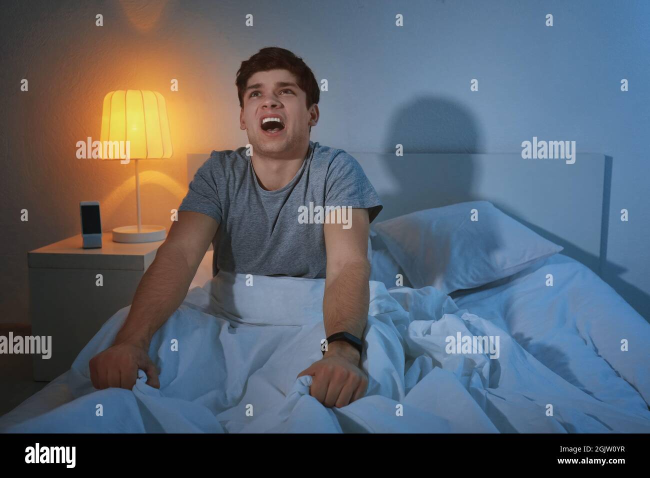 Young scared man sitting on bed at home Stock Photo - Alamy