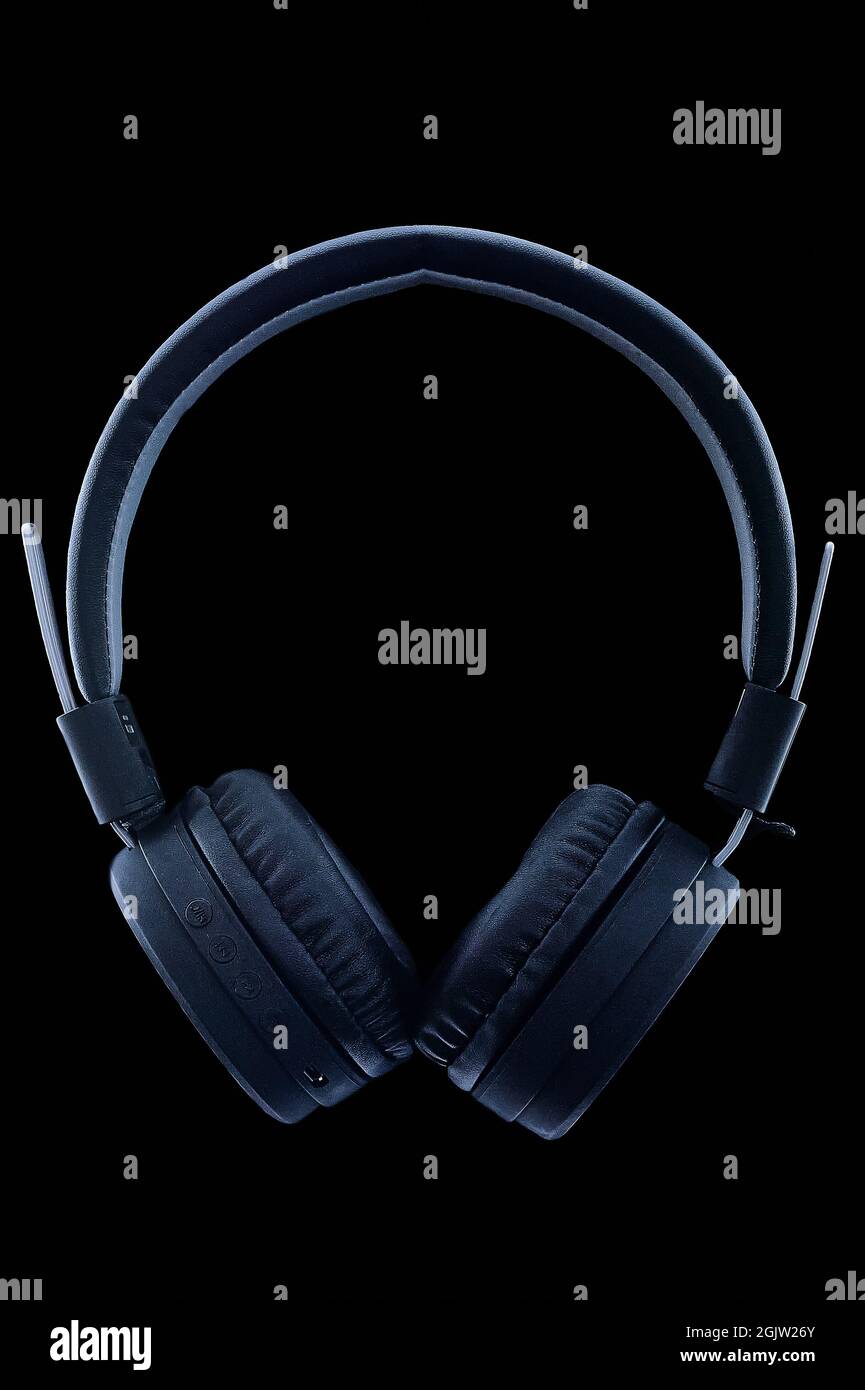 black wireless headphones on a black background Stock Photo - Alamy