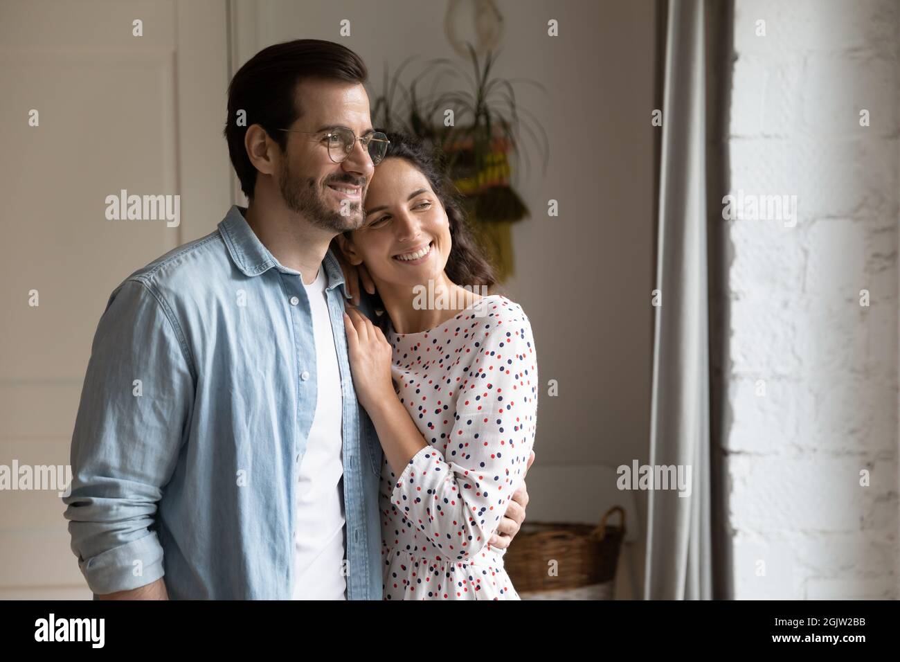 Lovely couple standing indoor looking into distance lost in dreams ...
