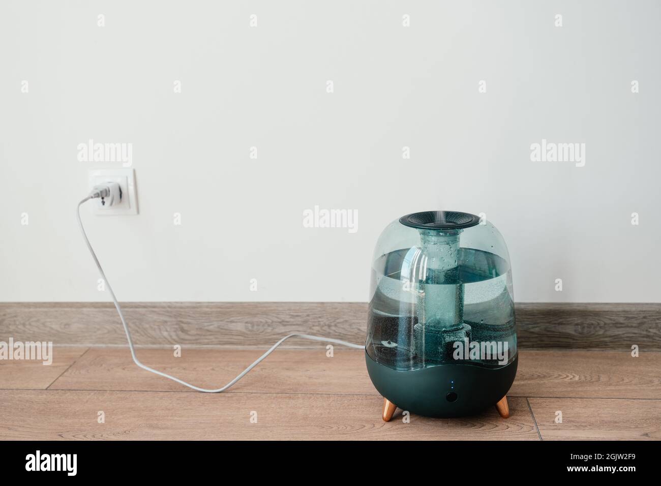 Modern air humidifier on a white wall background. Humidifier spreading ...