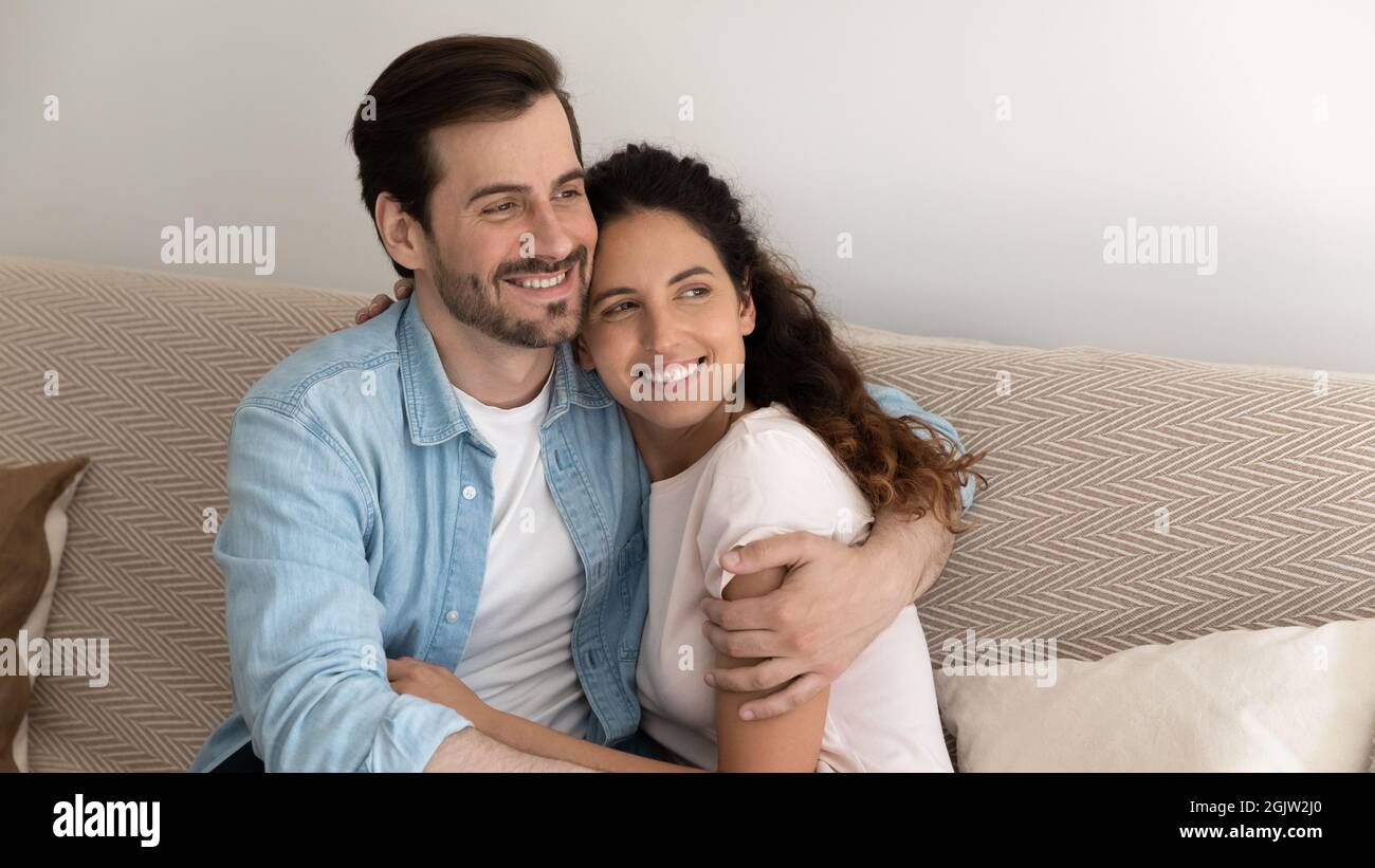 Couple in love hugging resting seated on couch at home Stock Photo - Alamy