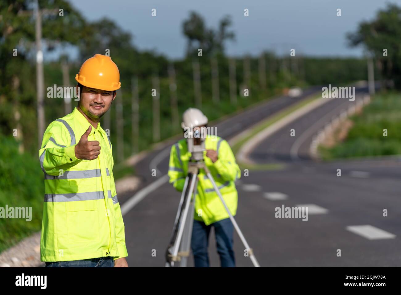 Asian happy surveyor engineers with digital level looking at camera on ...