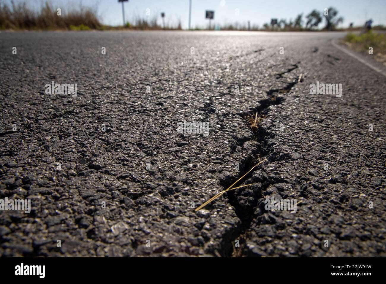 Close up of asphalt road surface crack with rural landscape in a ...