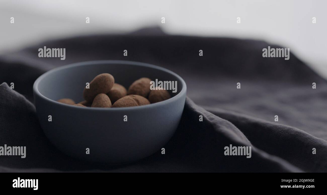 chocolate covered cocoa beans in blue bowl, wide photo Stock Photo - Alamy