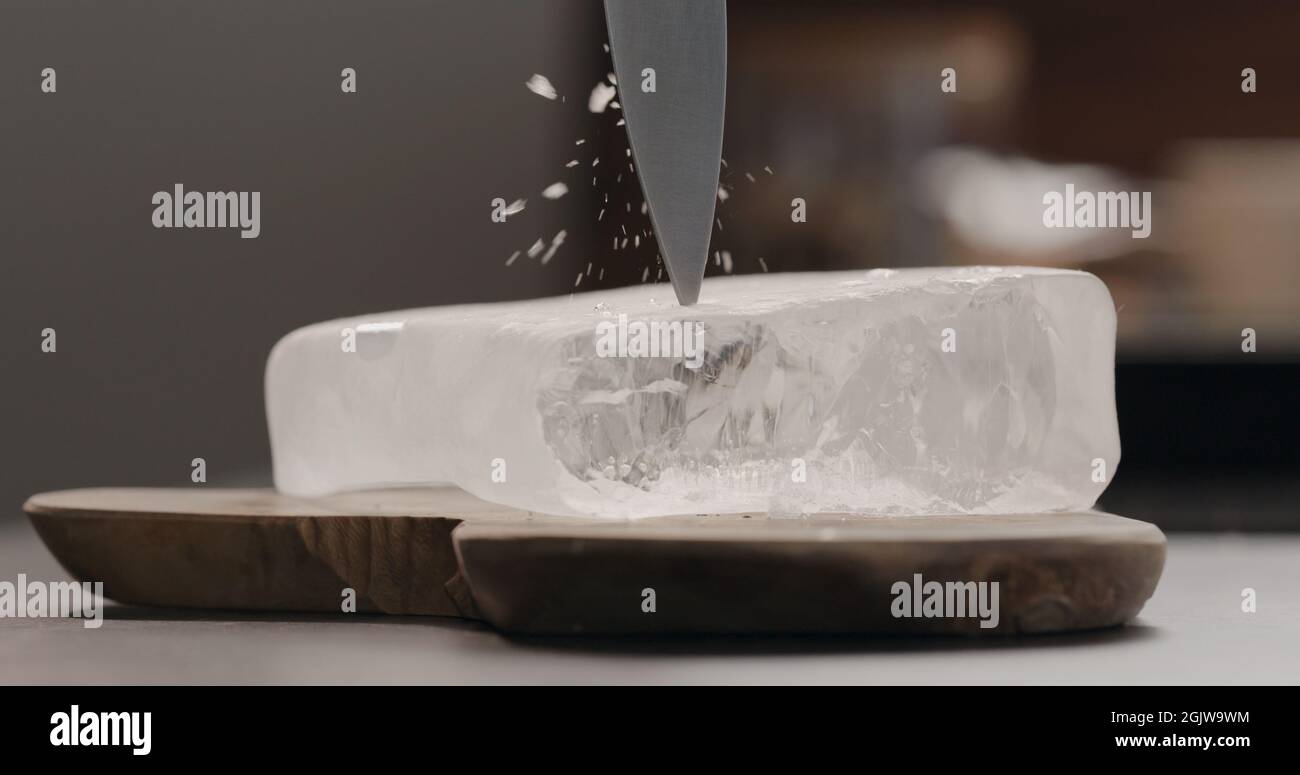 man breaking ice block on olive wood board, wide photo Stock Photo - Alamy