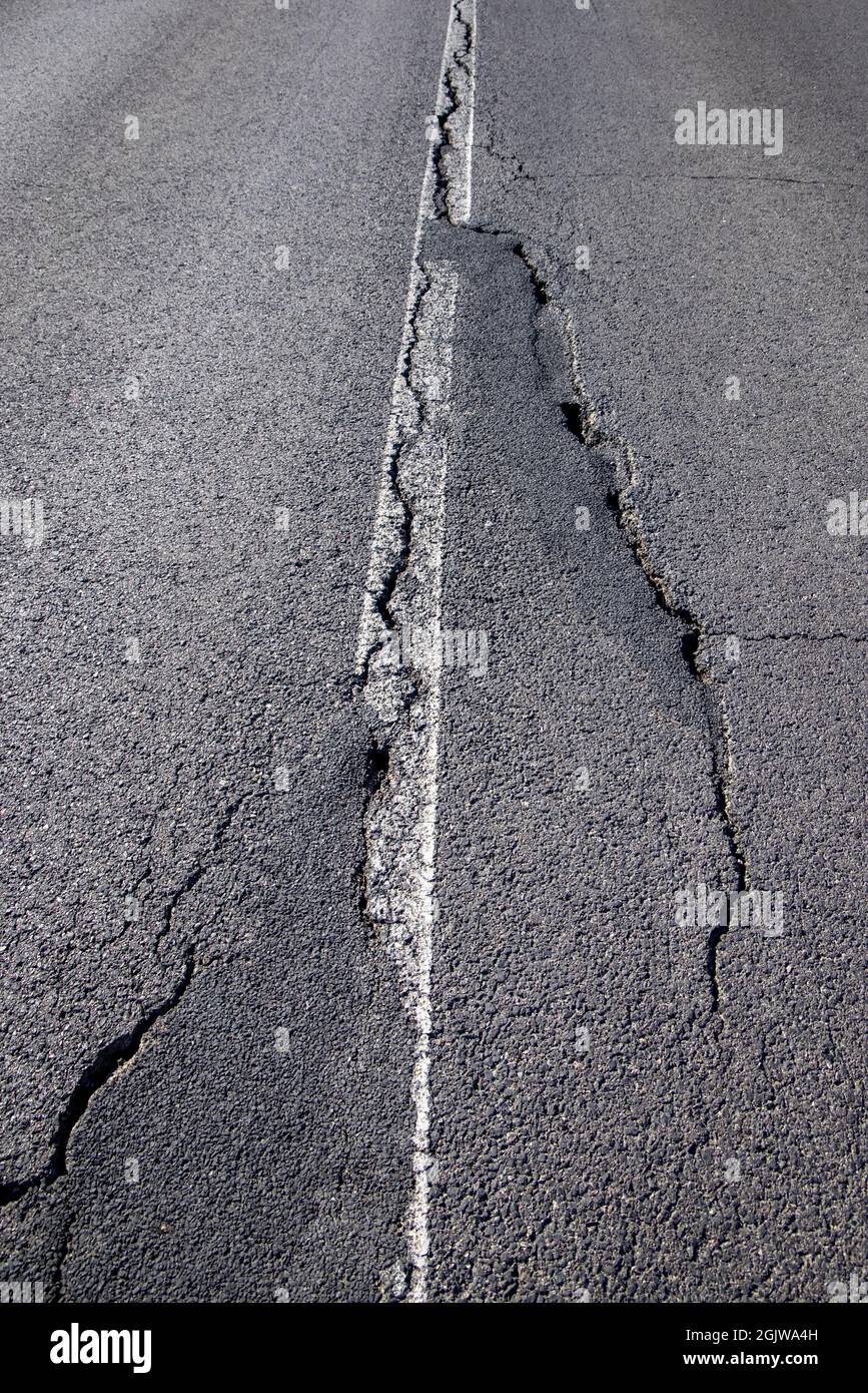 Close up of asphalt road surface crack with rural landscape in a ...