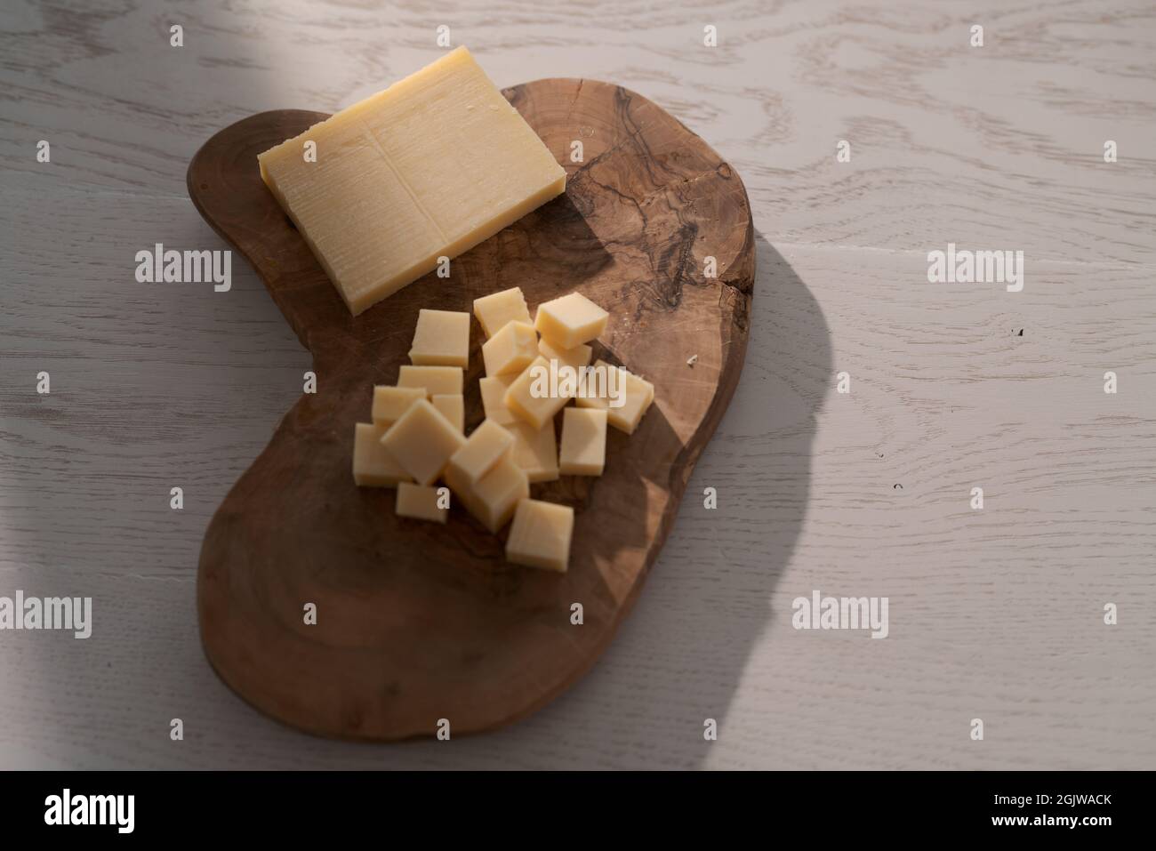 Small block of aged cheese sliced in small pieces on wood board ...