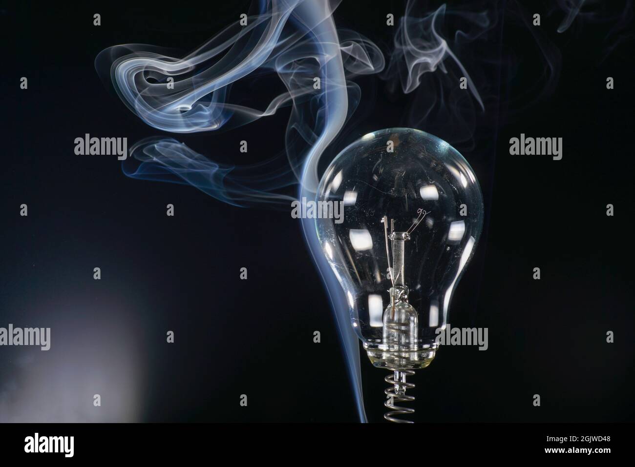 A lightbulb and smoke near it on a black background Stock Photo - Alamy