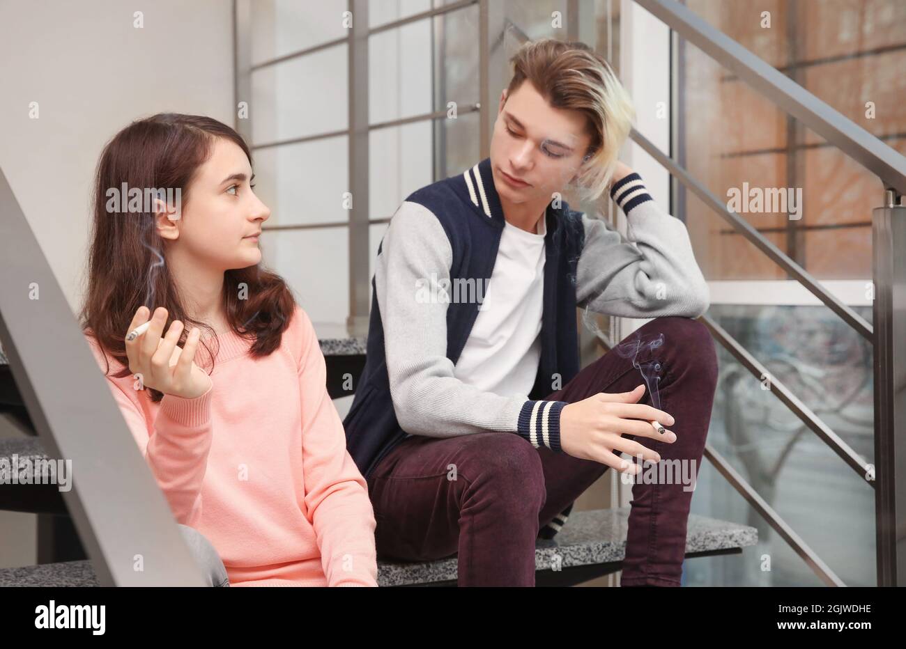 Teenage couple sitting on stairs and smoking Stock Photo - Alamy