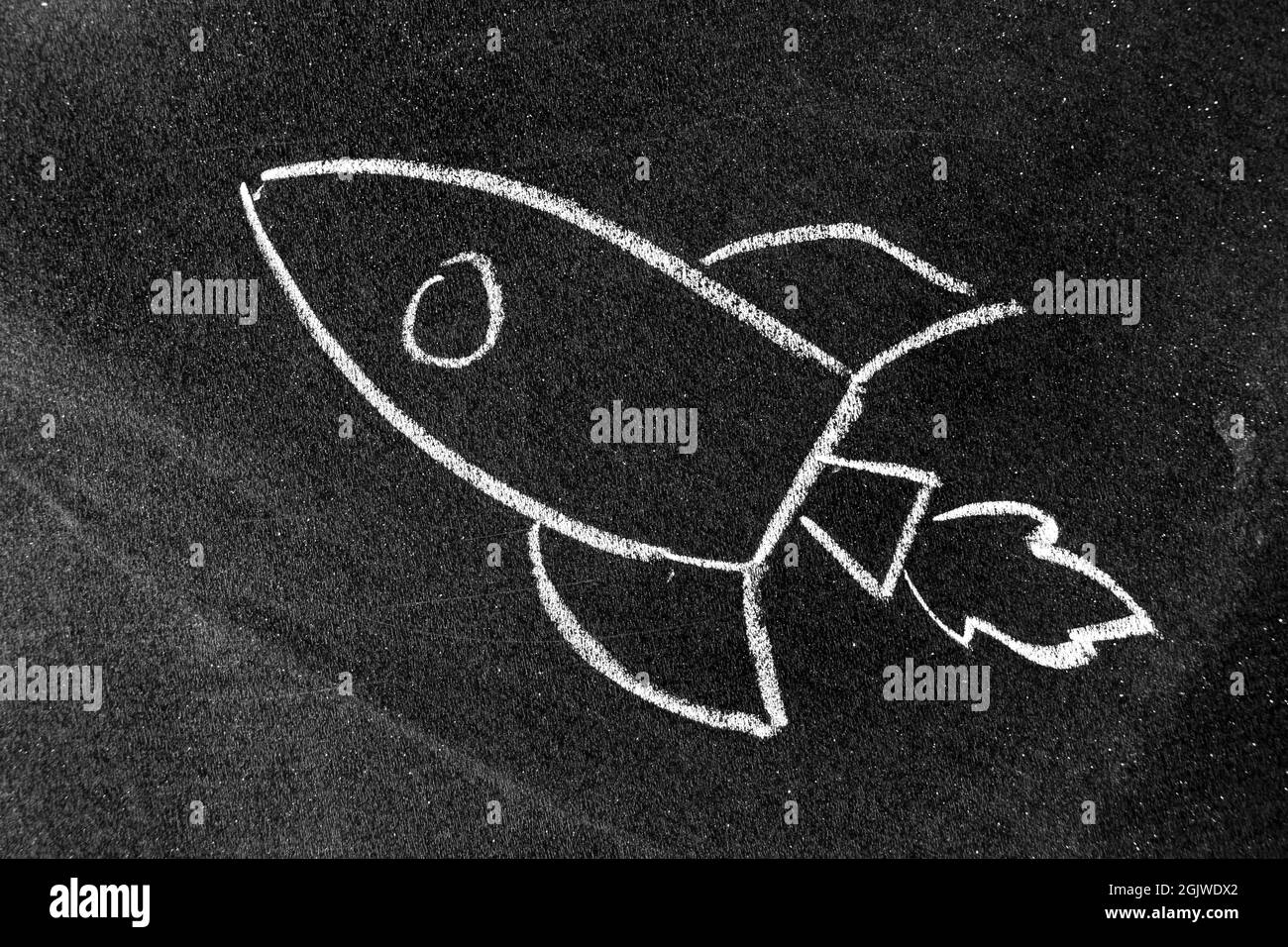 White color chalk hand drawing in rocket shape on blackboard or ...