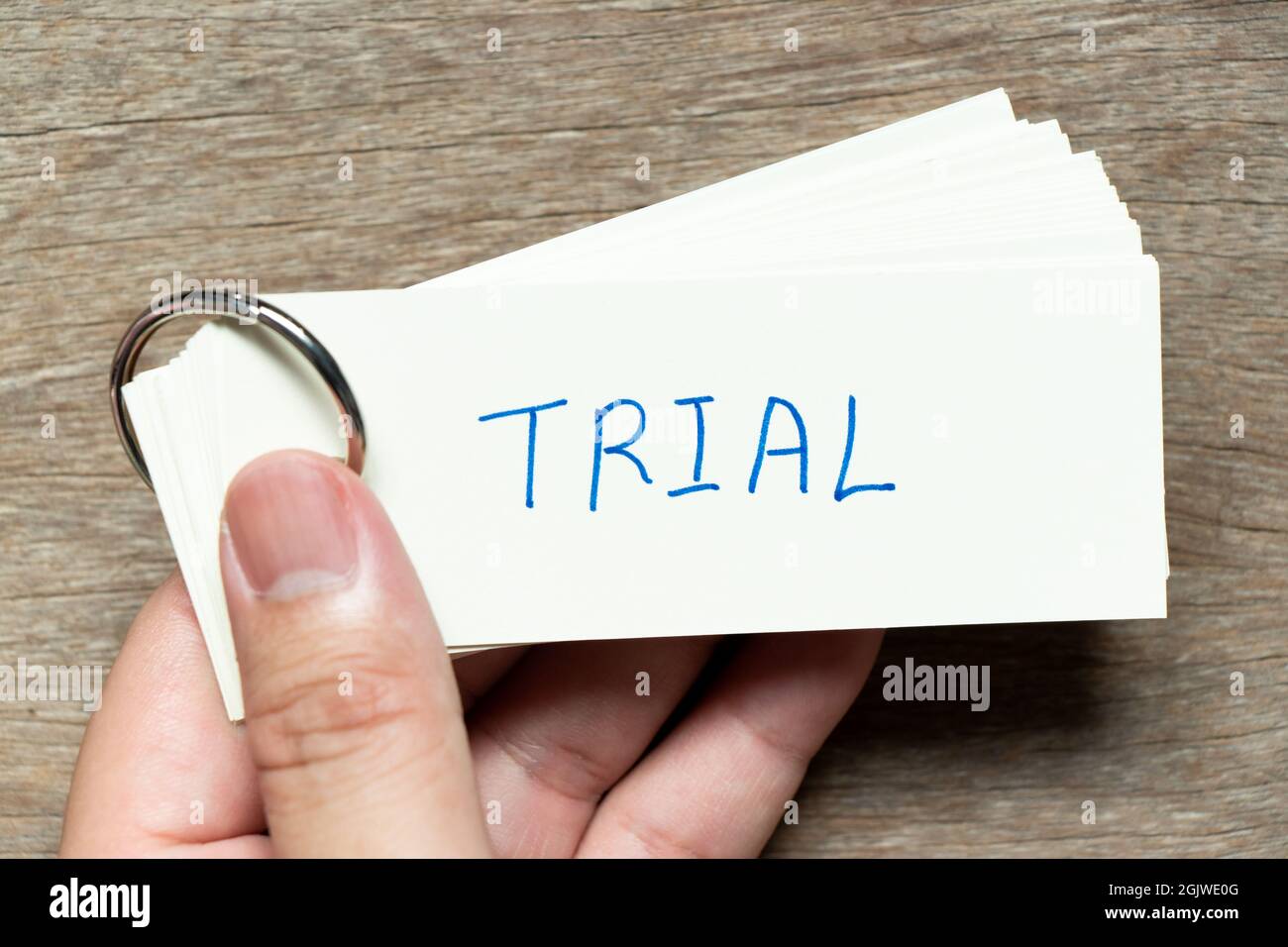 Man hold the flash card with handwriting word trial on wood background ...