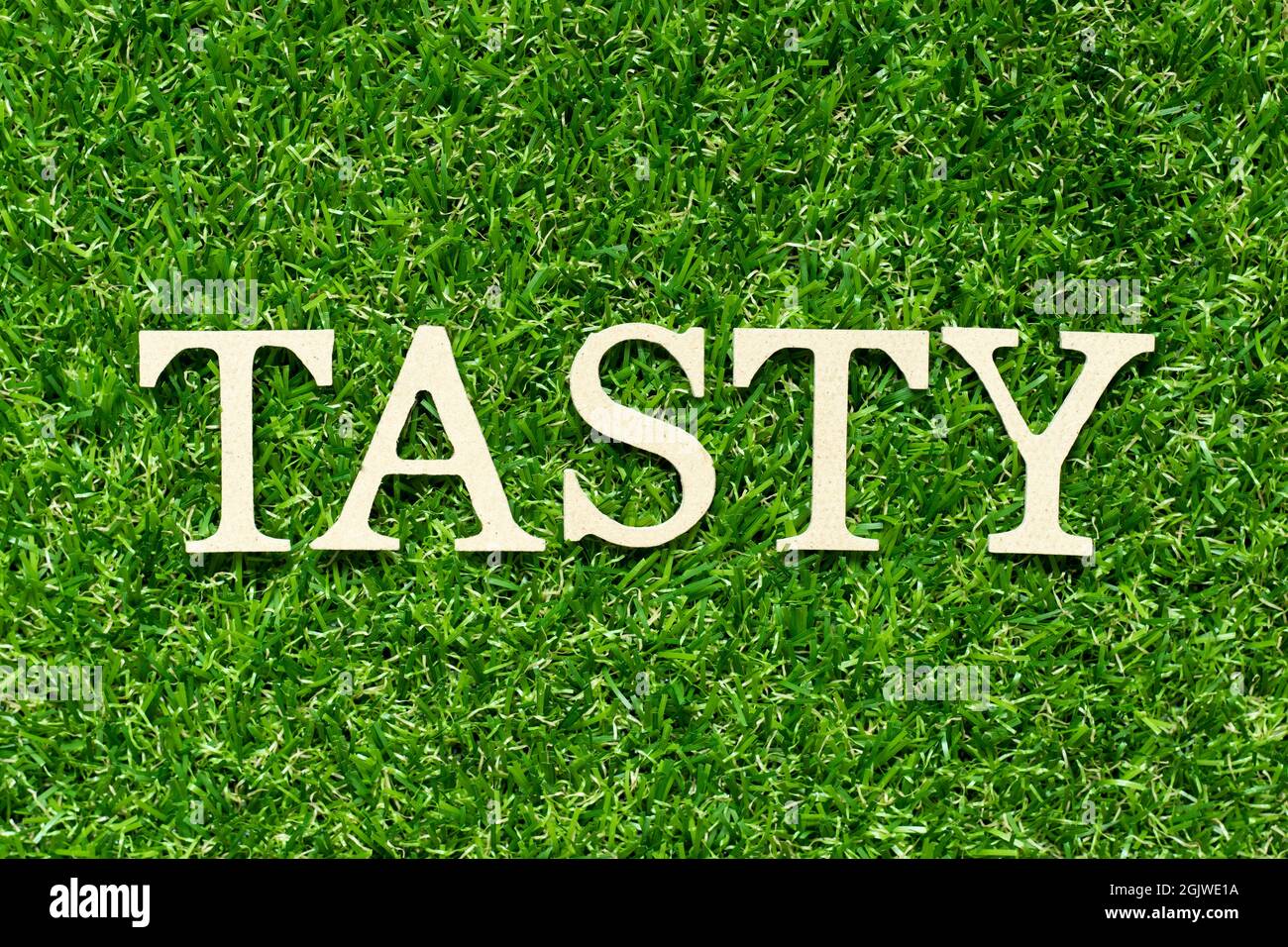Wood letter in word tasty on green grass background Stock Photo - Alamy