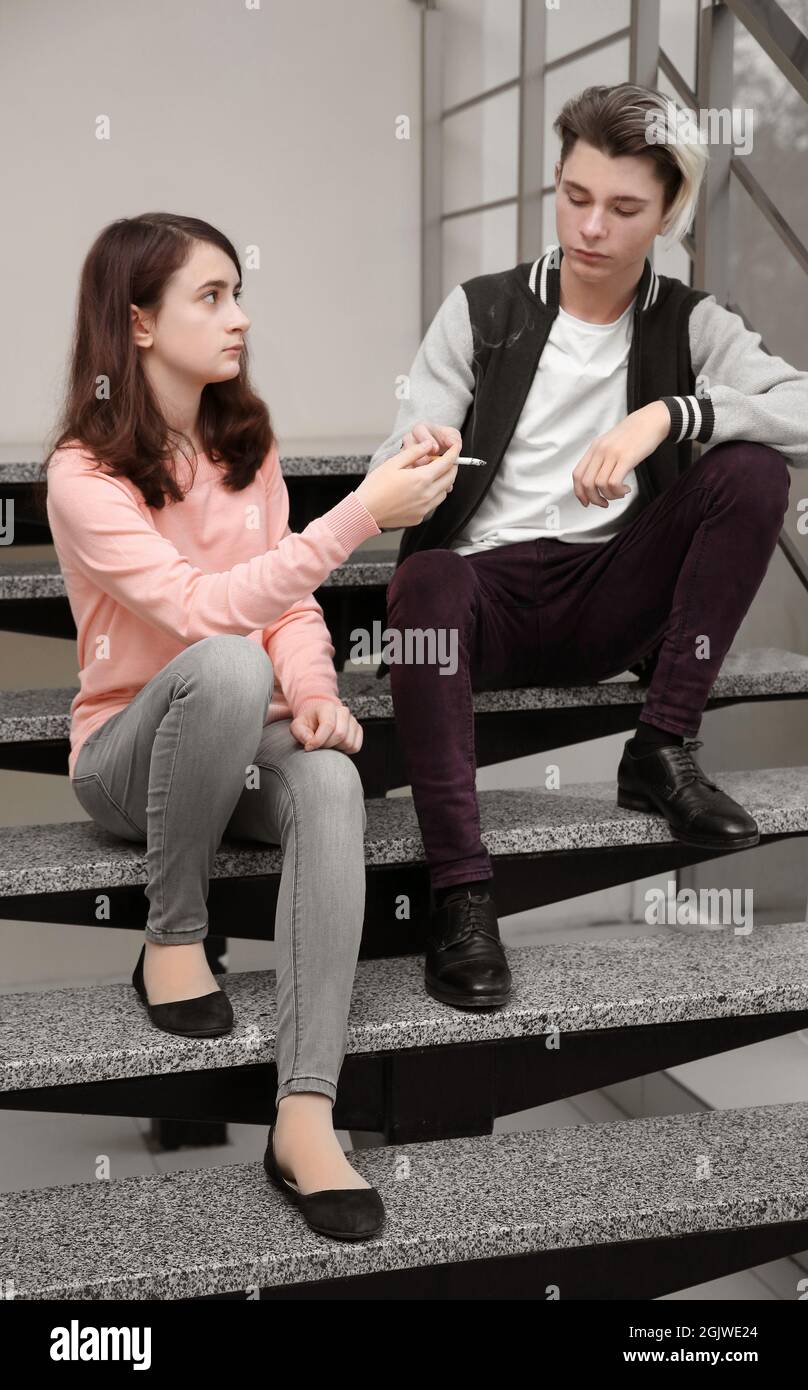 Teenage couple sitting on stairs and smoking Stock Photo - Alamy