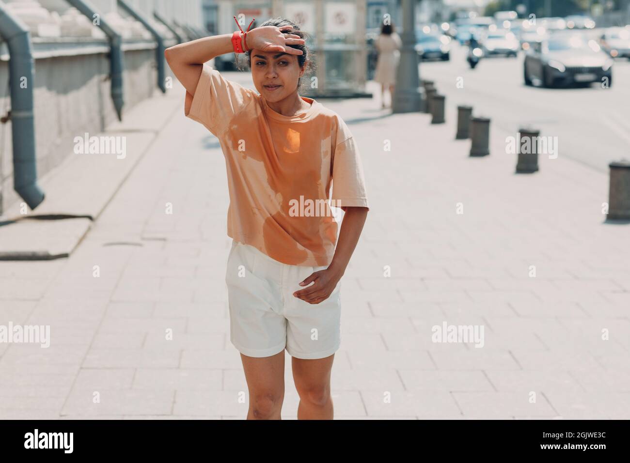 Young indian woman runner jogging in wet sweaty t-shirt at city street ...