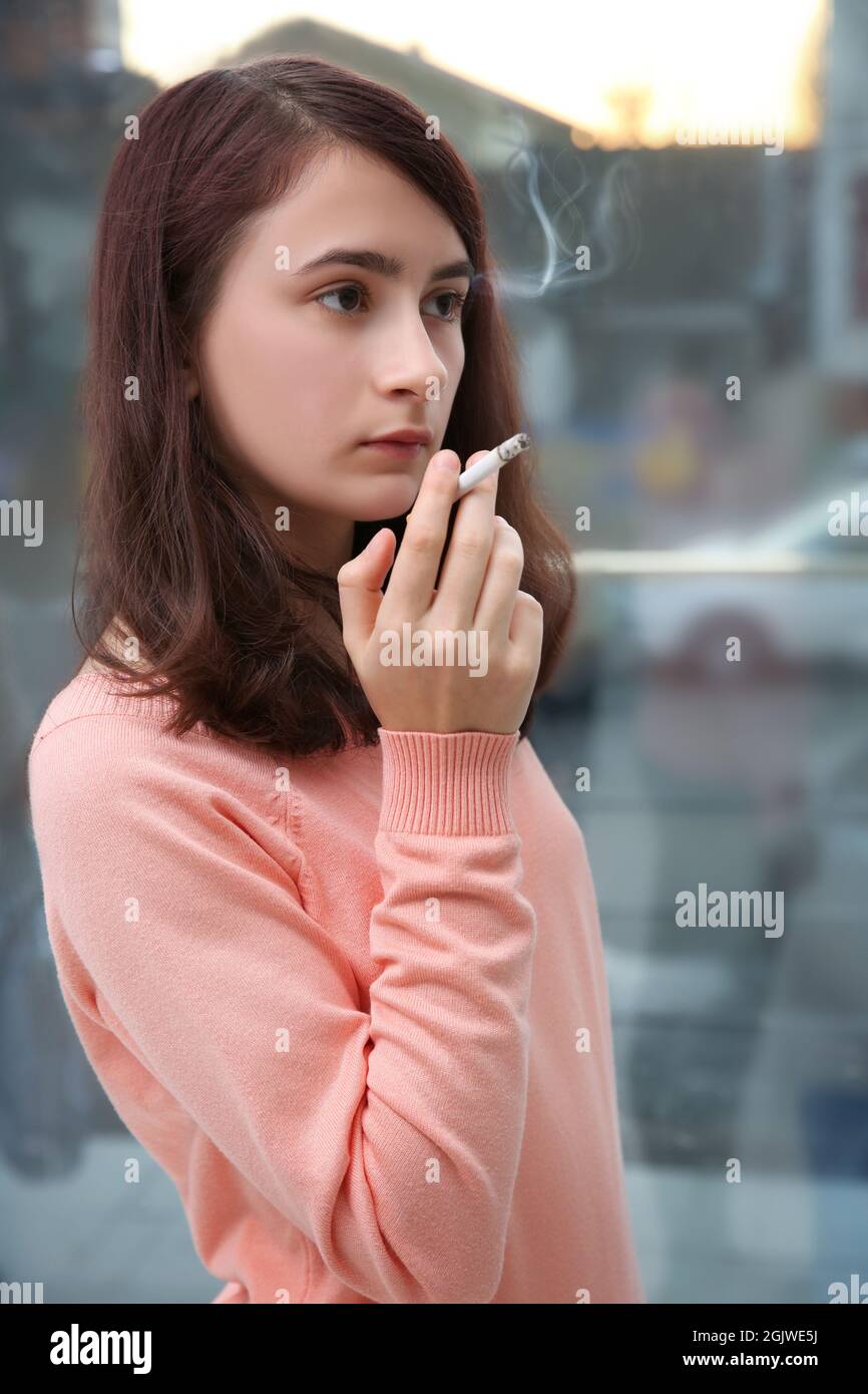 Teenage girl smoking on window background Stock Photo - Alamy