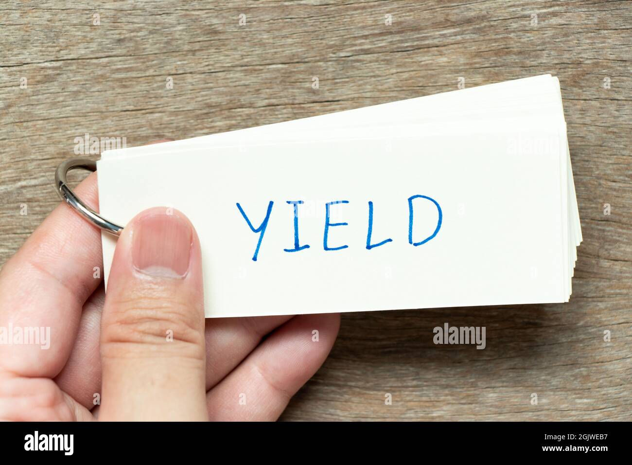 Man hold the flash card with handwriting word yield on wood background ...