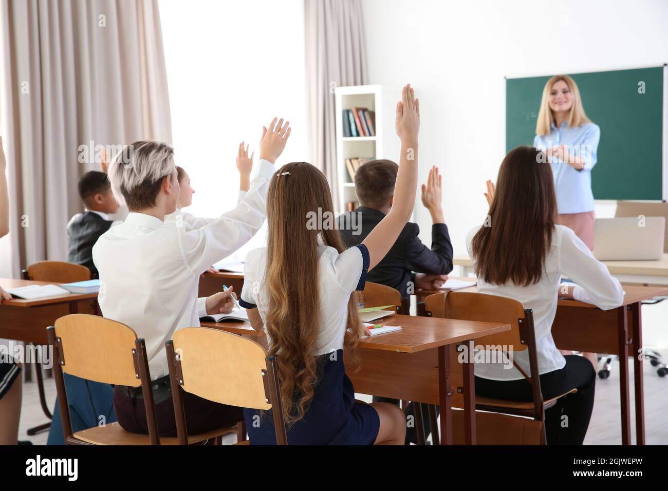 Teenagers in classroom raising hands hi-res stock photography and ...