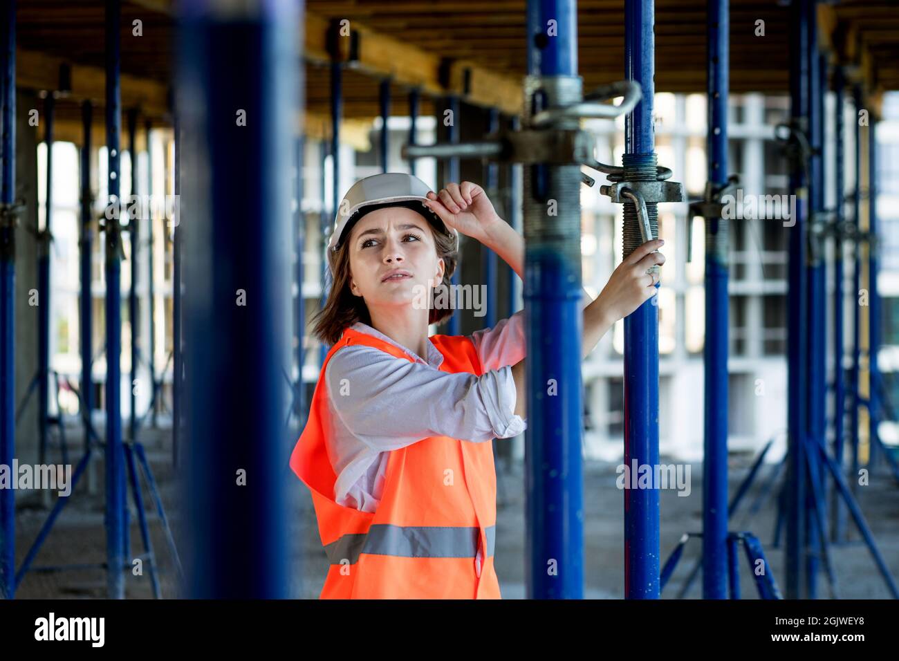 Confident Female builder checks fastenings on a monolithic structure ...