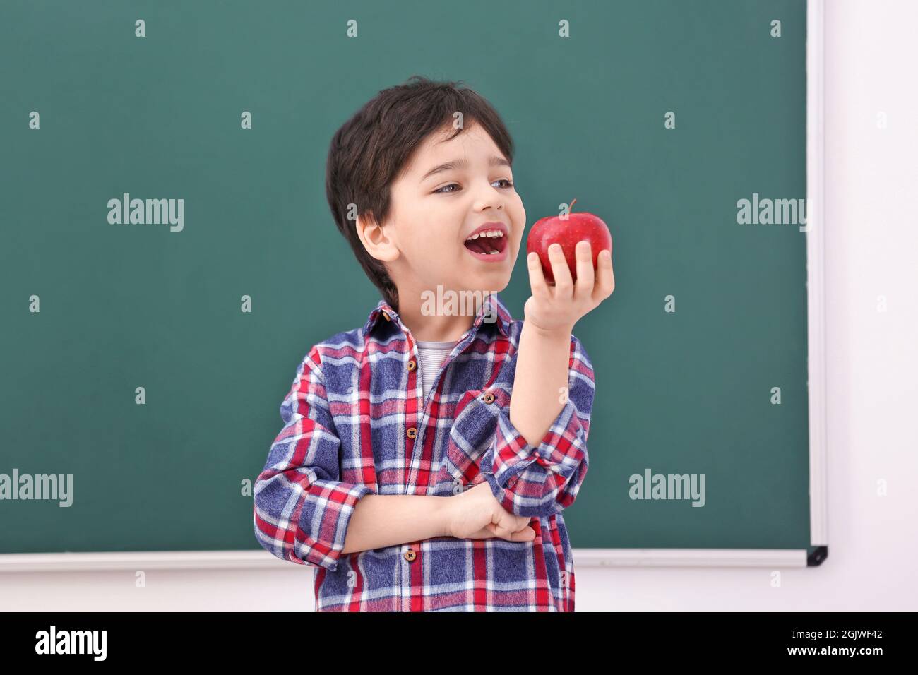 Cute little boy with apple in classroom Stock Photo - Alamy
