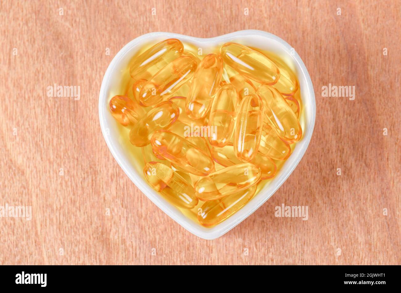 Heart-shape plate with fish oil capsules on wooden background Stock ...