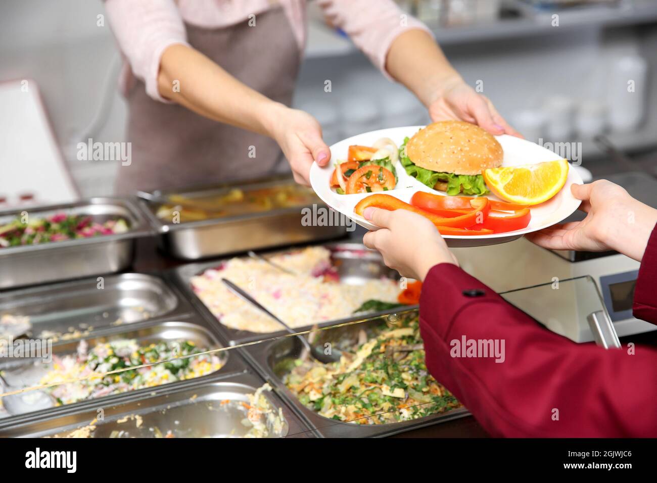 Pleasant woman giving lunch to school girl in cafeteria Stock Photo - Alamy