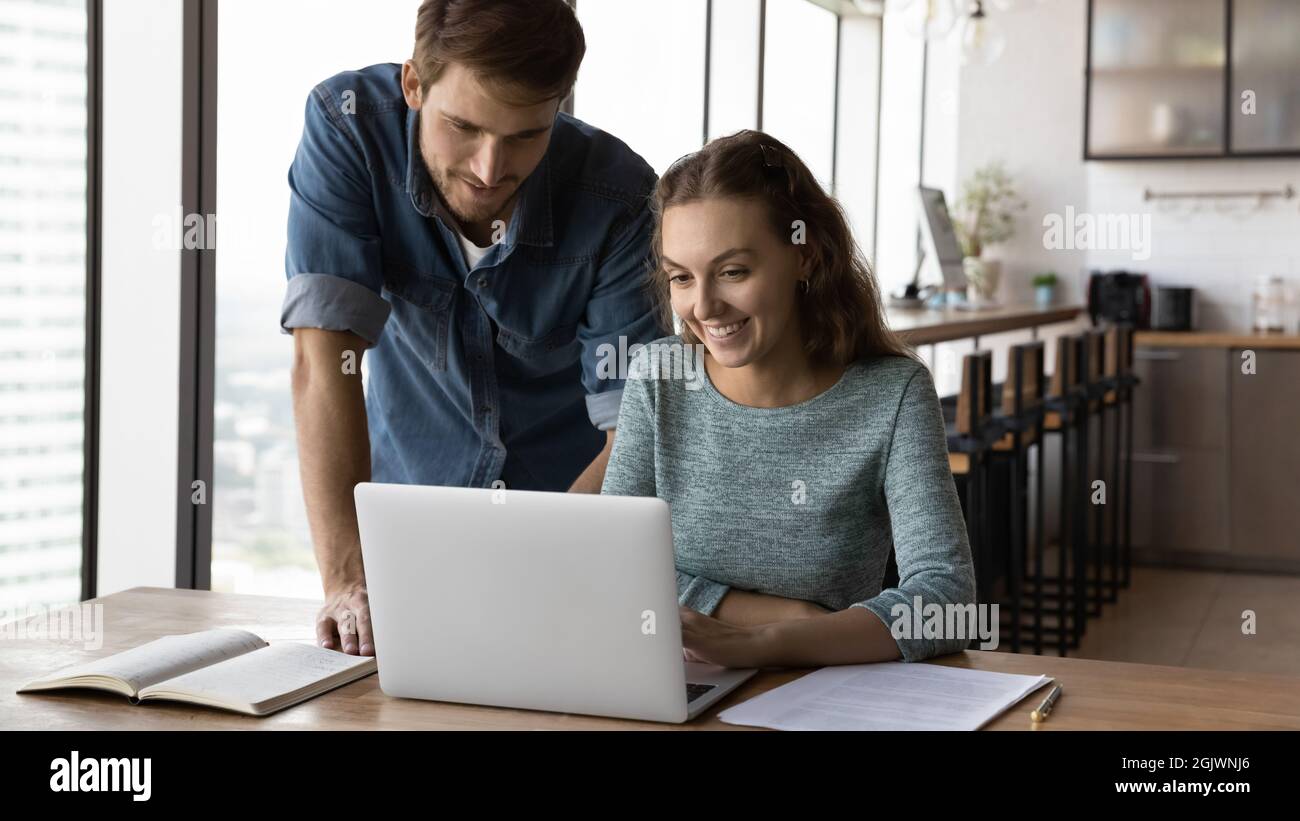 Smiling employees work together on laptop discuss ideas Stock Photo - Alamy