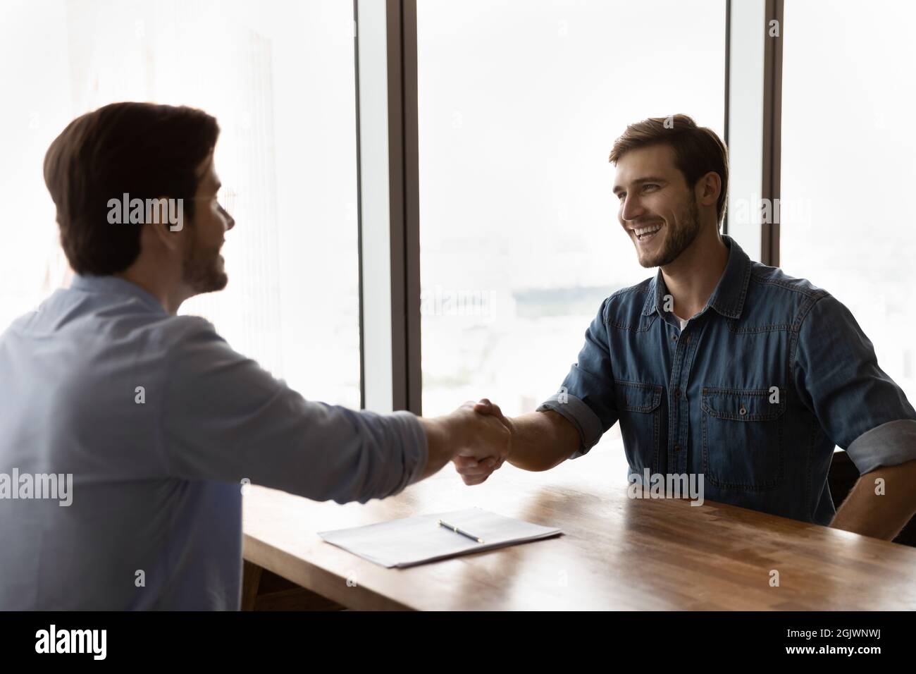 Smiling male employee handshake closing deal at meeting Stock Photo - Alamy