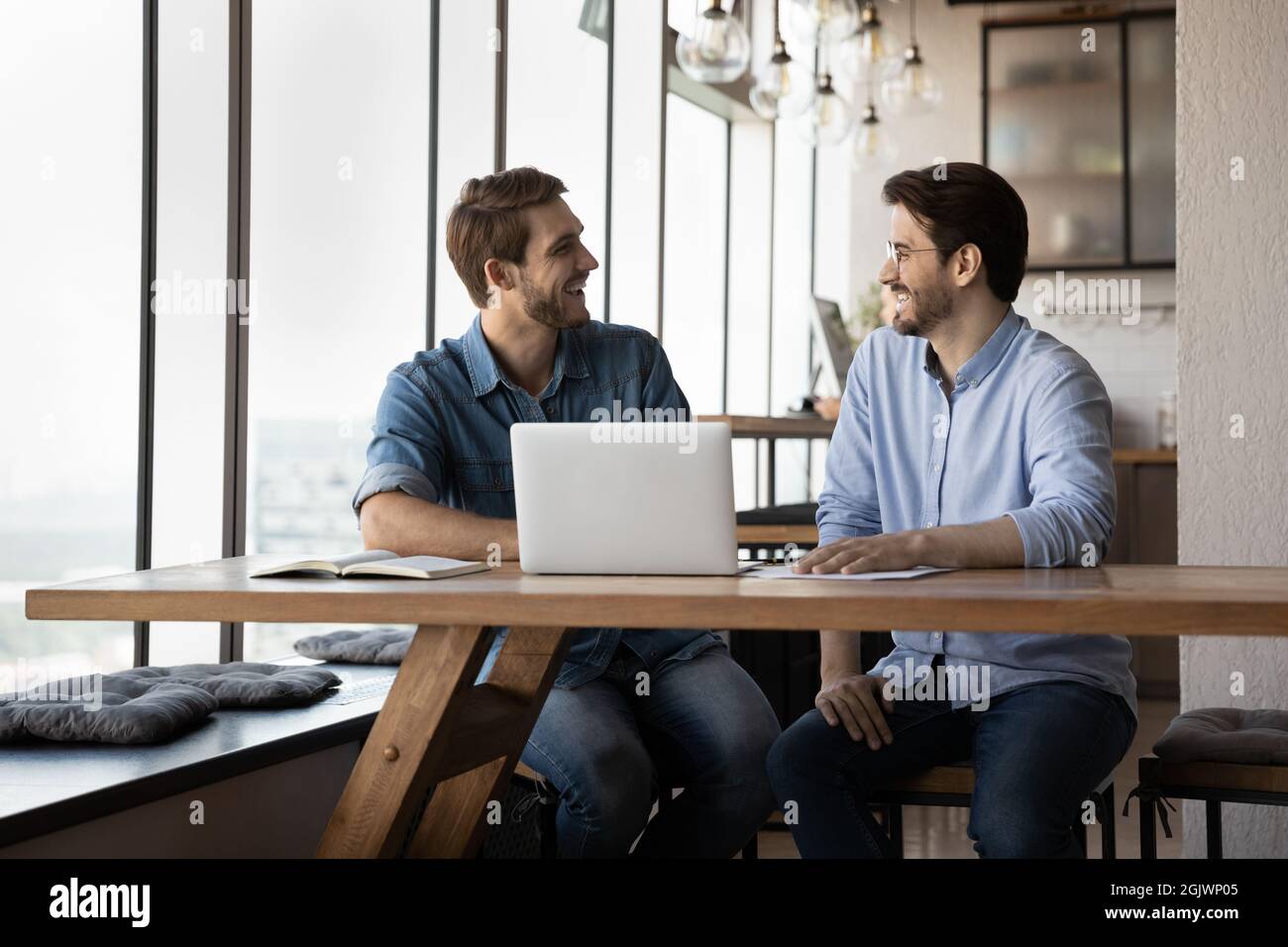 Smiling male colleagues joke working together on computer Stock Photo ...