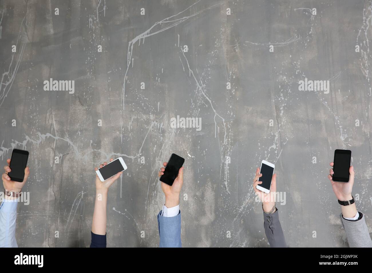 People raising hands with smartphones on gray textured background Stock ...
