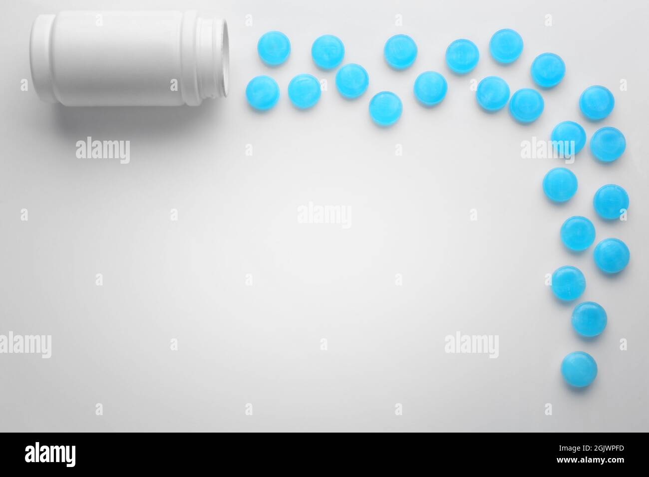 Cough drops spilling out of bottle on white background Stock Photo - Alamy