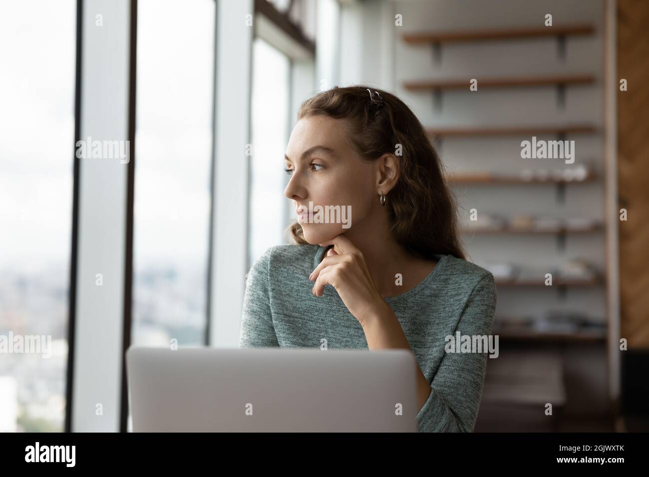 Pensive female employee work on laptop thinking Stock Photo - Alamy