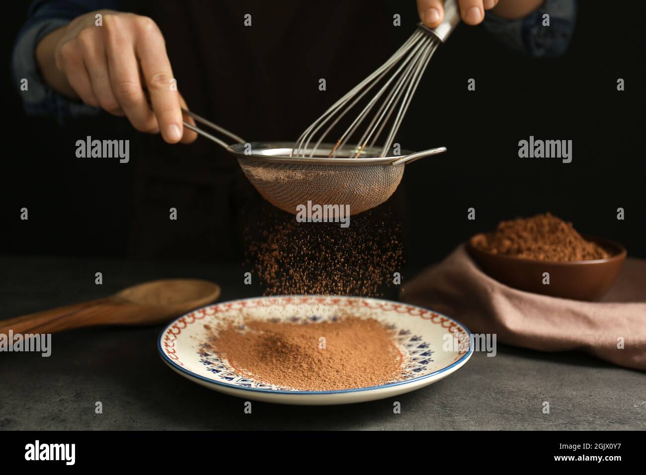 Female hands with sieve and corolla powdering cocoa onto plate Stock ...