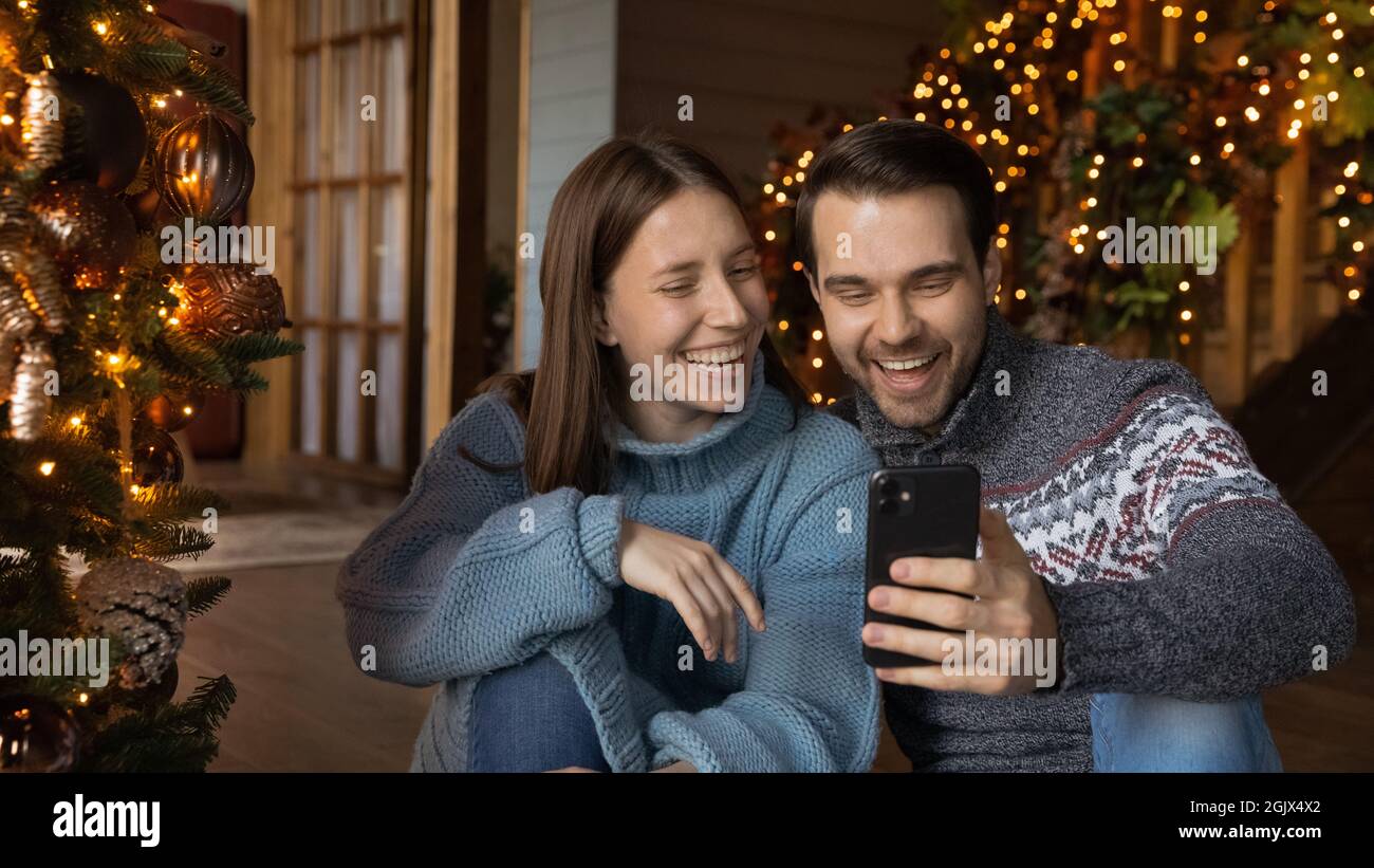 Smiling positive young european bonding couple looking at smartphone ...