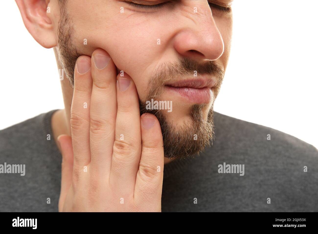 Handsome man suffering from toothache on white background, closeup ...