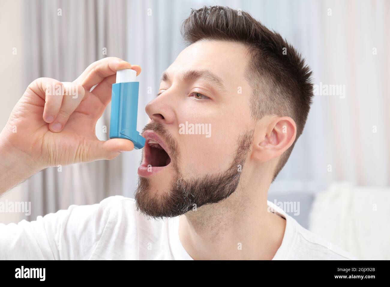 Young man using asthma inhaler at home Stock Photo - Alamy