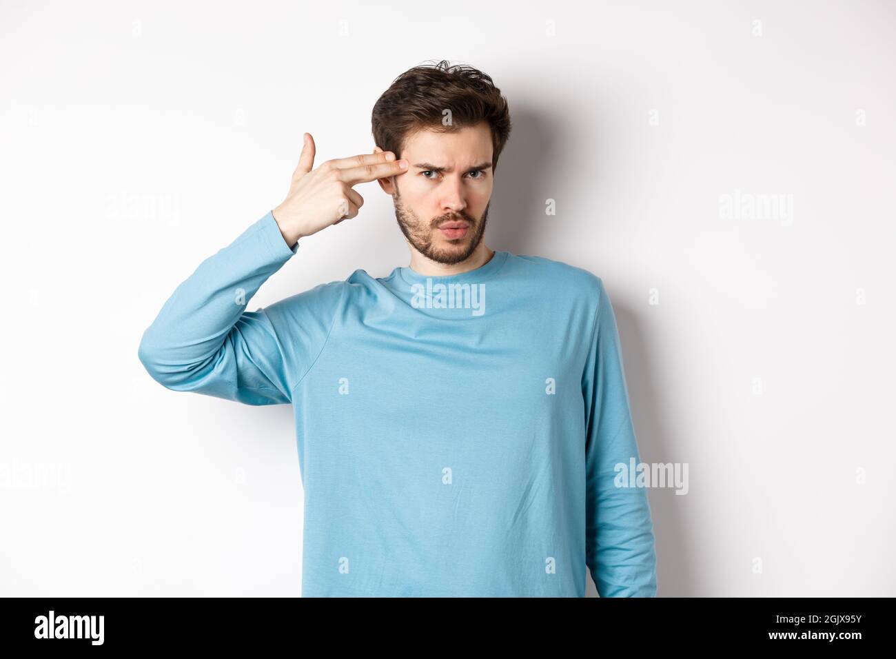 Annoyed young man frowning, showing shooting gun near head gesture ...