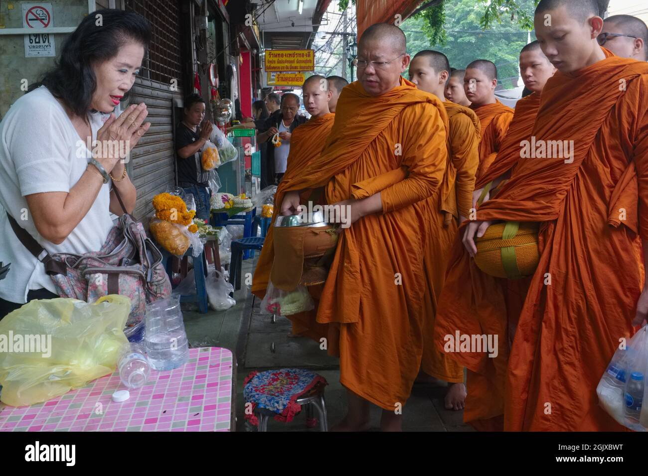 Proffering a traditional Thai wai (greeting) a lay woman greets a group ...