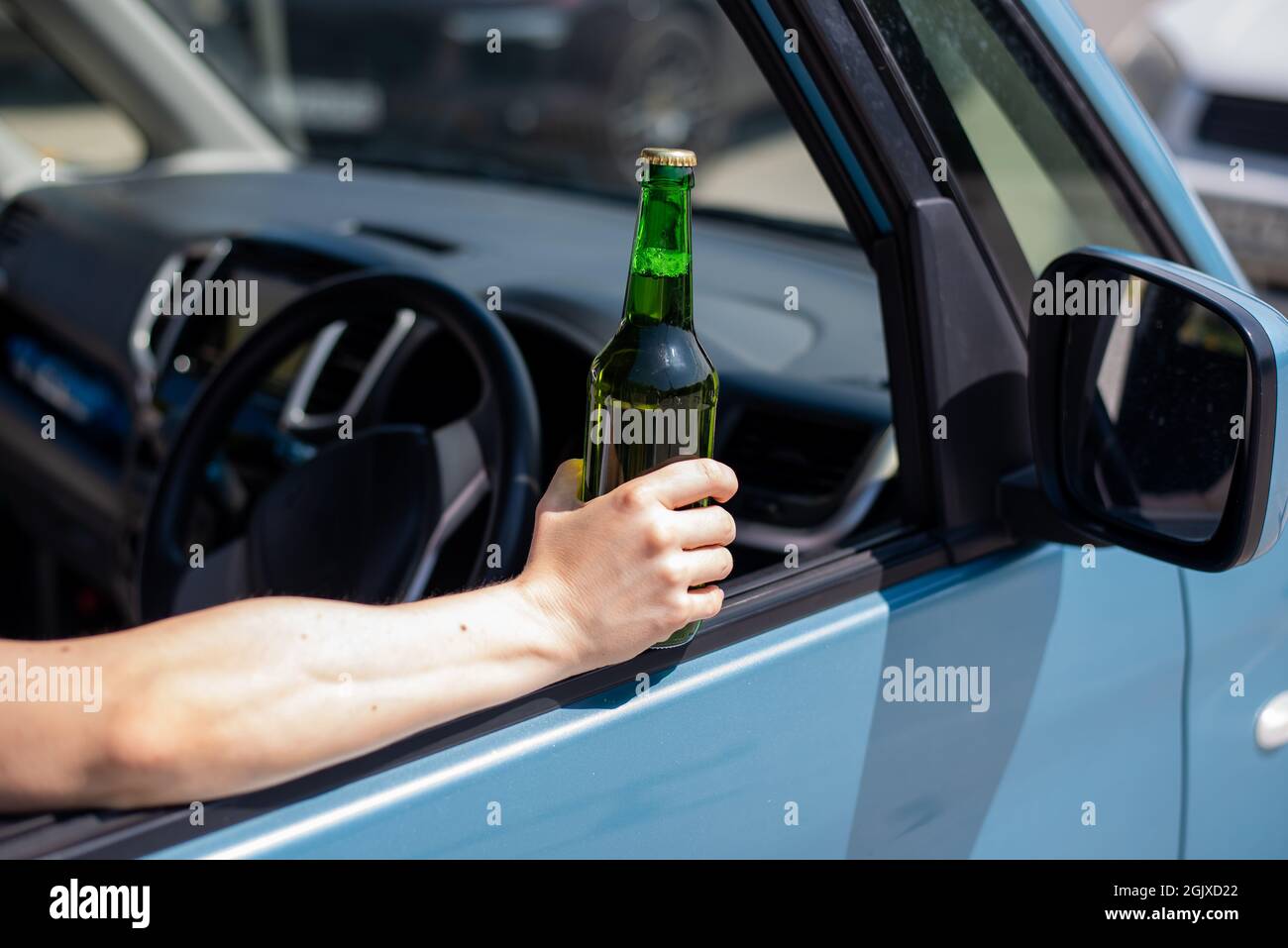 A faceless woman is drinking a bottle of beer while driving a car ...