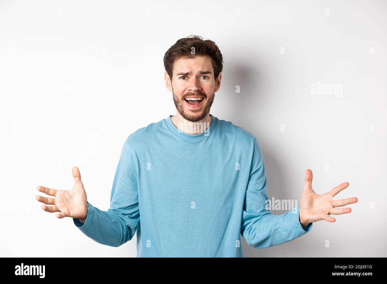Image of frustrated and worried young man shaking hands, trying to ...