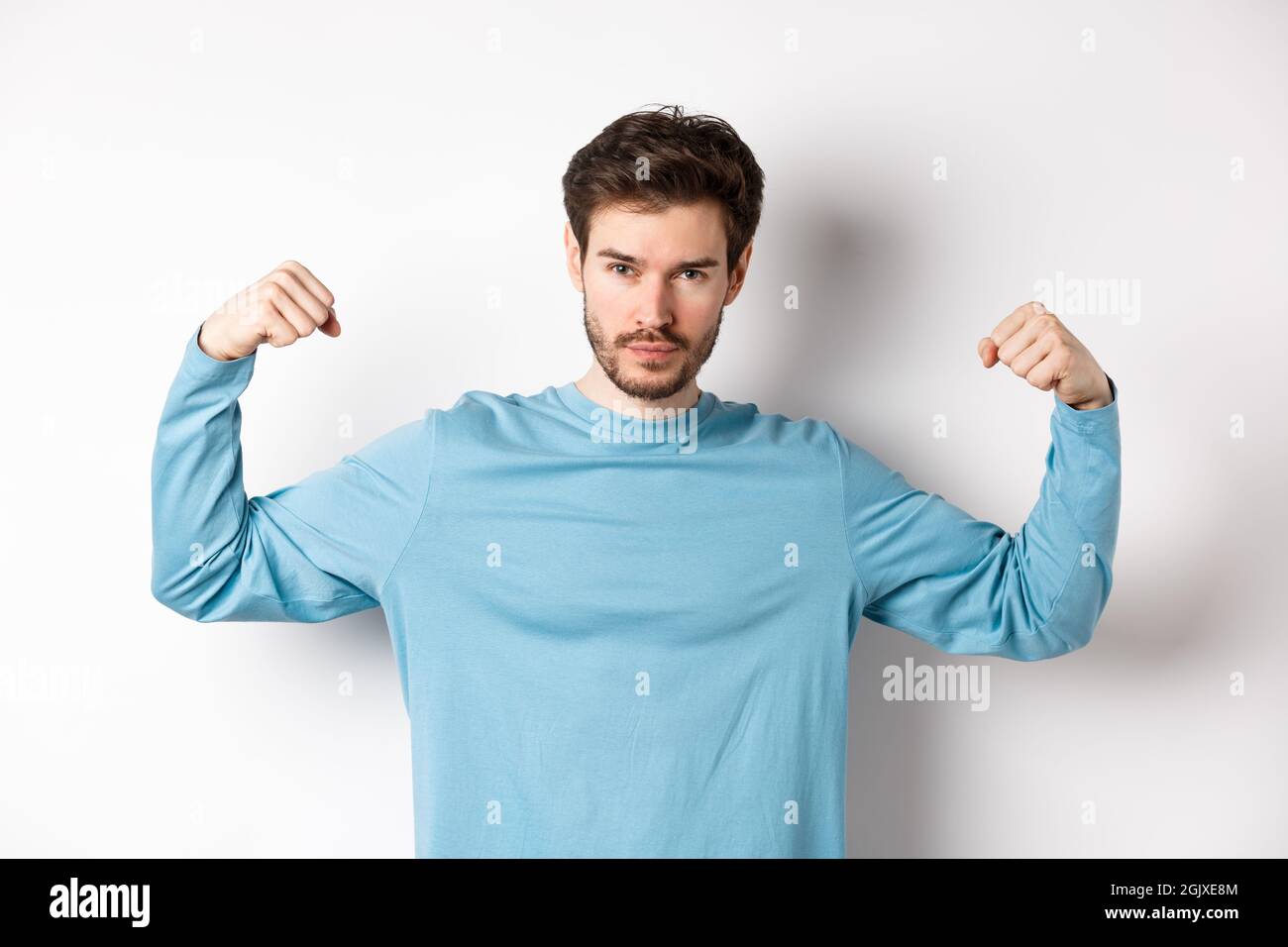 Confident and strong macho man flexing biceps, showing strength in ...