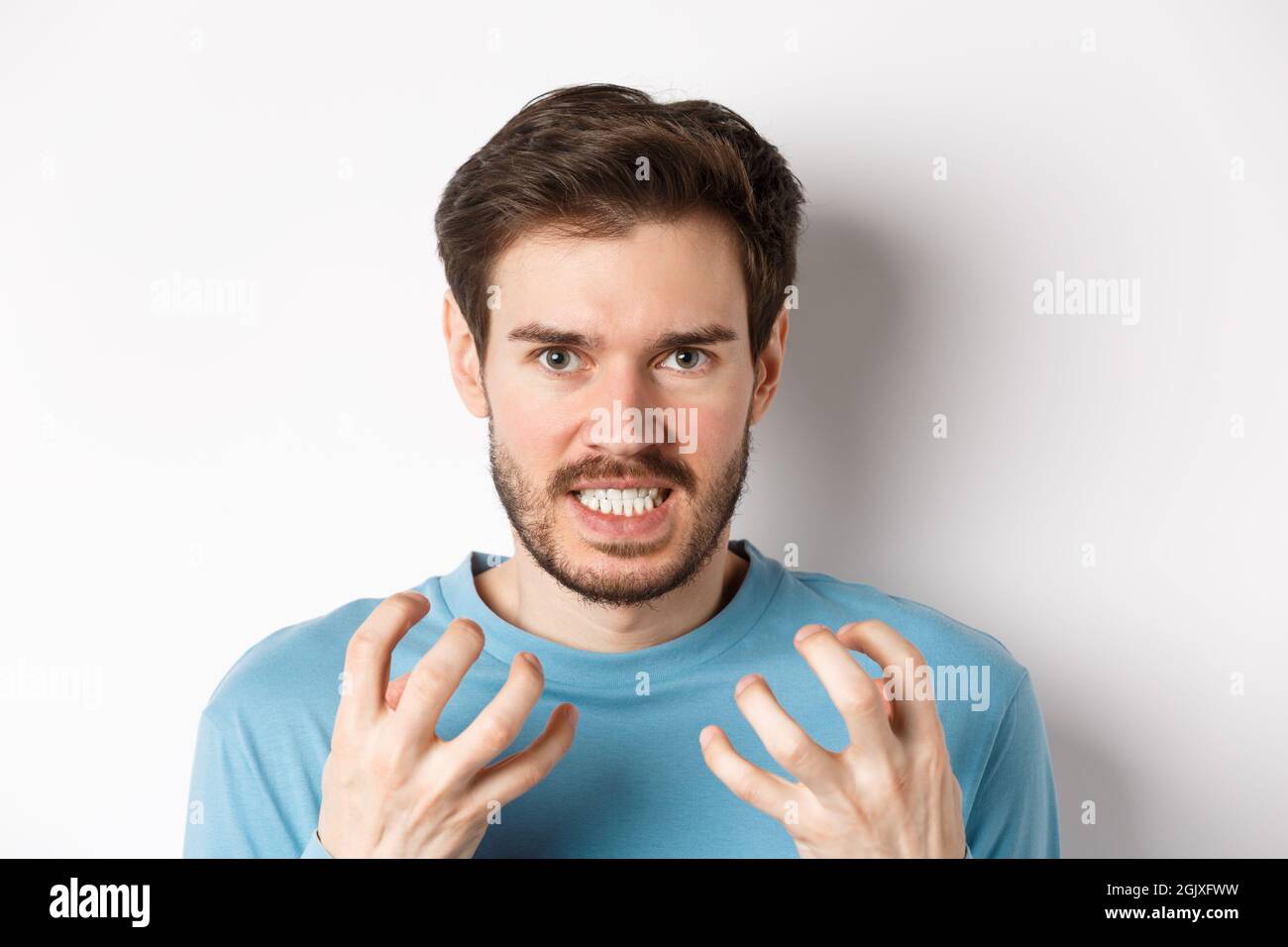 Close up of angry young man with beard, shaking hands mad, squeeze ...